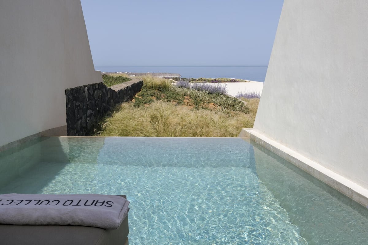 Visão nítida de uma piscina, uma toalha com a etiqueta 'SART' e vista para o mar e vegetação costeira.
