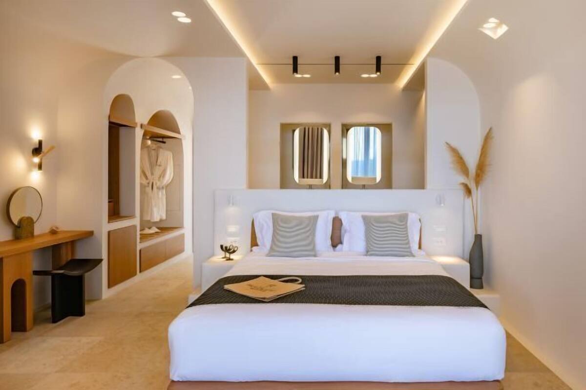 Quarto moderno com cama grande, mesas de cabeceira, penteadeira e closet espaçoso.