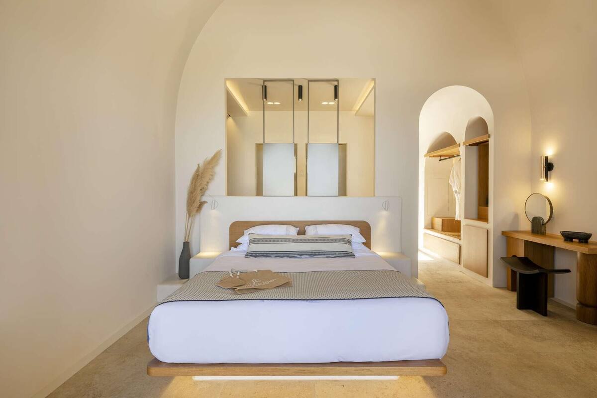 Um quarto moderno com uma cama grande, um espelho sobre a cama e uma toucador com espelho e luzes.