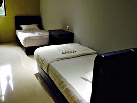 Quarto de hotel com duas camas, uma mesa de cabeceira e uma janela.