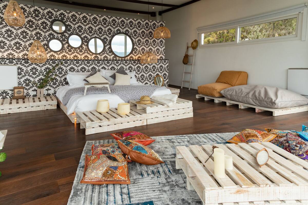 Quarto com cama, mesas de cabeceira, uma cadeira e janela.