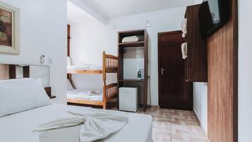 Quarto com beliche, pequena geladeira, guarda-roupa de madeira e televisão fixada na parede.