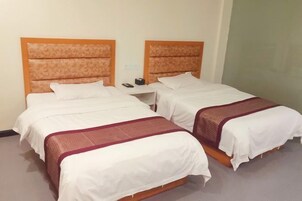 Quarto de hotel com duas camas de solteiro, cada uma com cabeceira de madeira e roupa de cama branca.