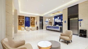 Um saguão de hotel moderno com balcão de recepção, área de estar e elevador.