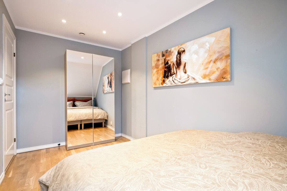 Quarto com uma cama grande, um espelho e uma pintura na parede.