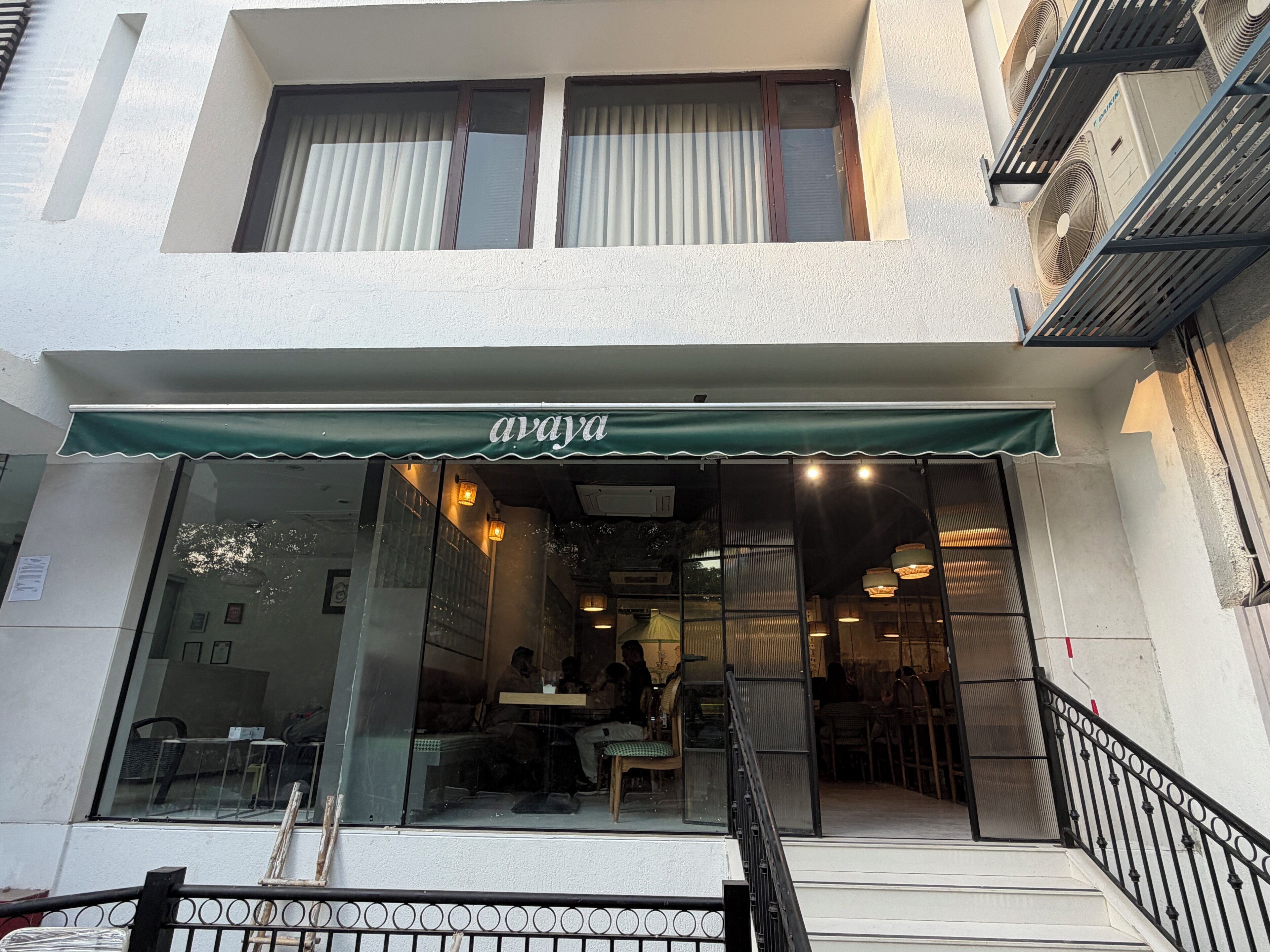 Um café com toldo verde e mesas ao ar livre.