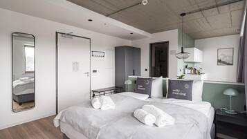 Quarto moderno com cama grande, mesa de cabeceira, espelho e guarda-roupa.