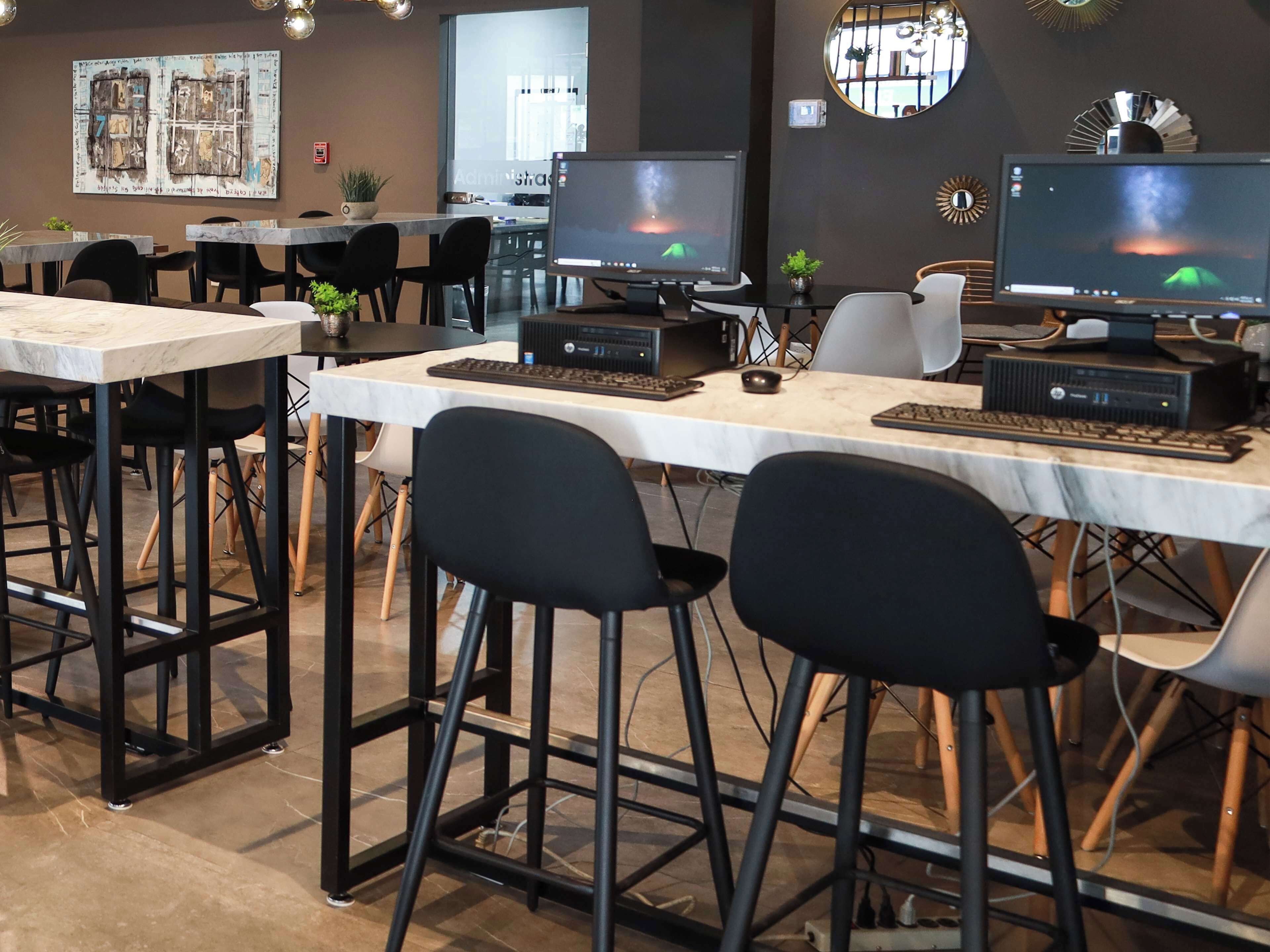 Um espaço de escritório moderno com várias mesas, cadeiras e computadores.