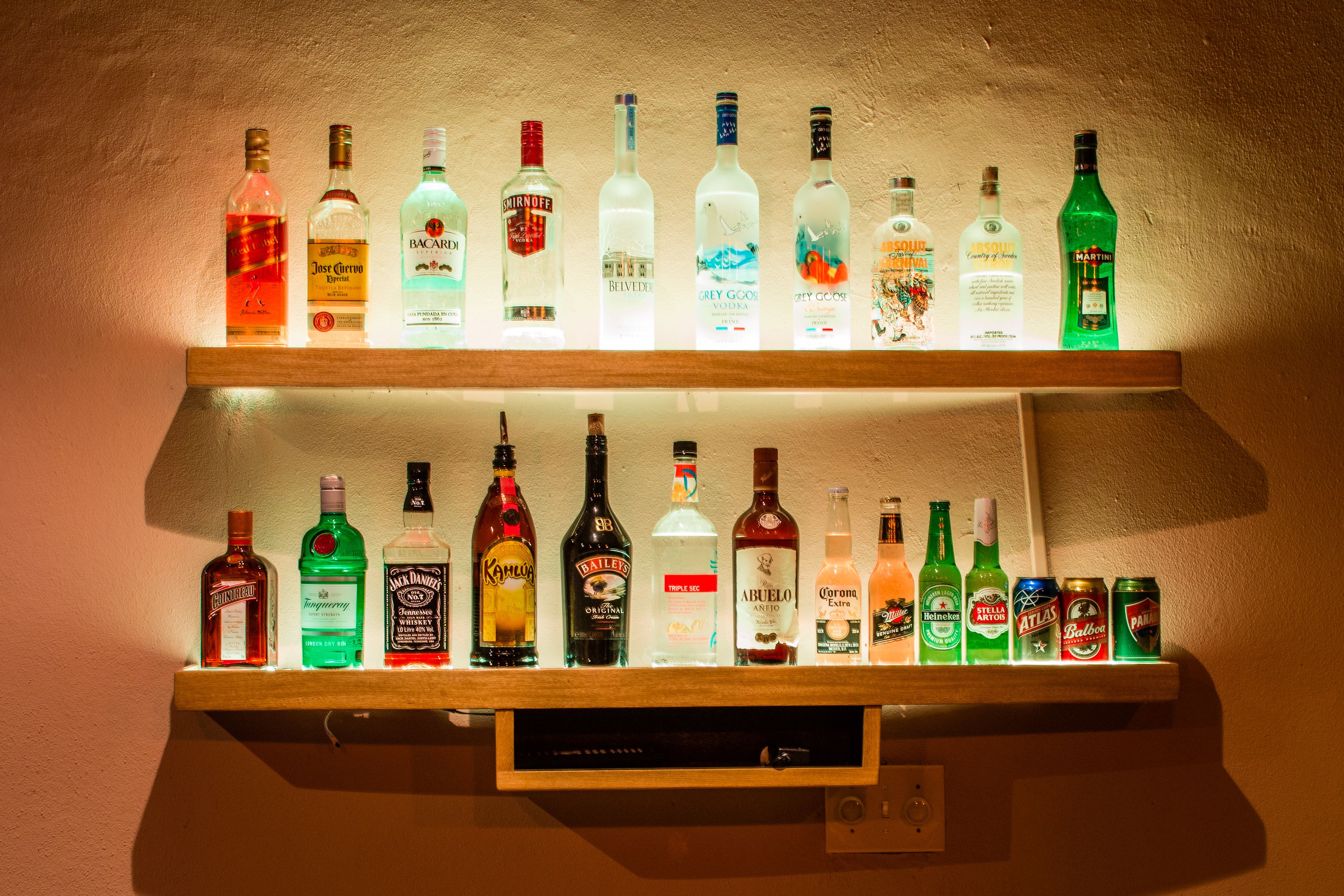 Duas prateleiras com diversas garrafas de bebidas alcoólicas.