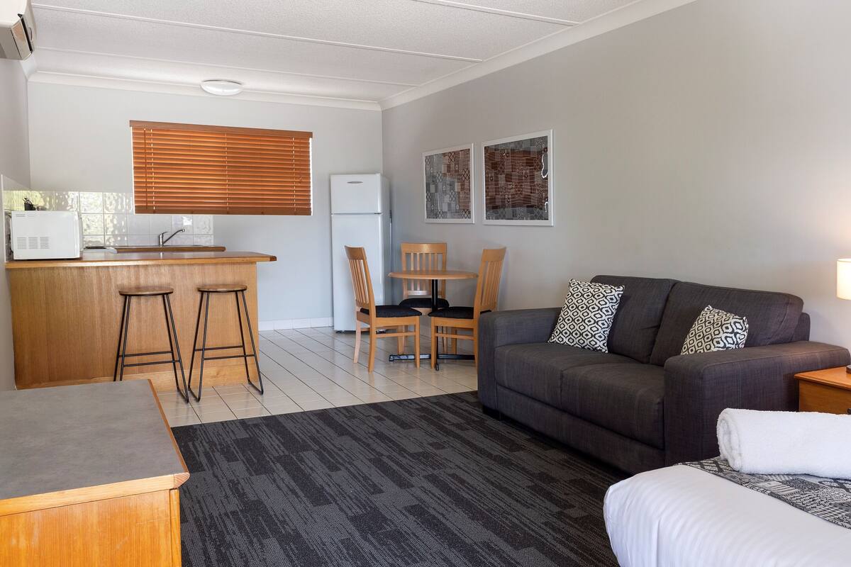 Um espaço compacto com cozinha compacta, sofá, área de refeições e cama.