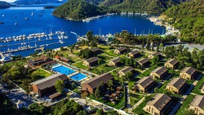 Resort costeiro com marina, piscina e vários edifícios tipo bungalow.