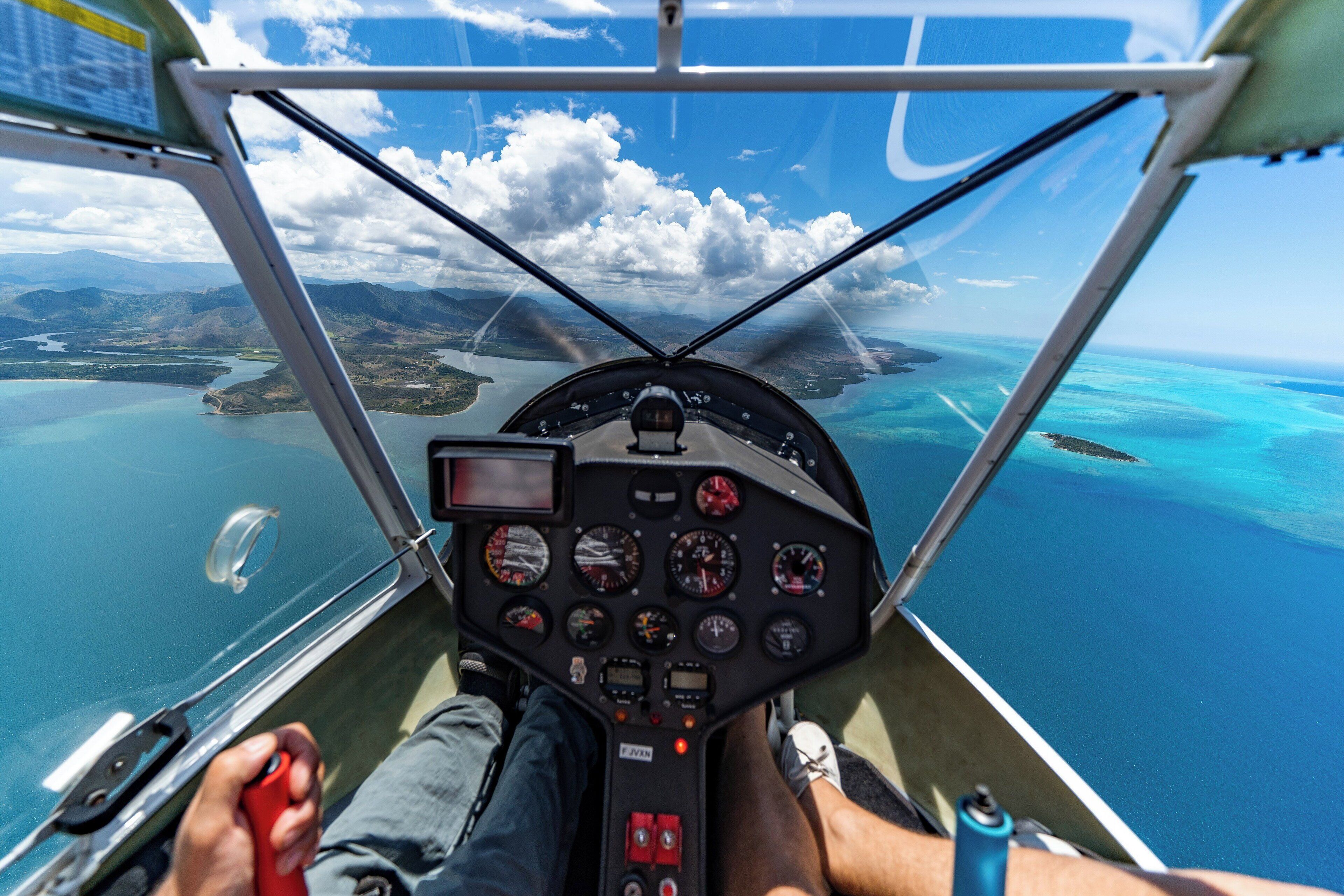 Visão da cabine com céu claro, água e terra ao longe.