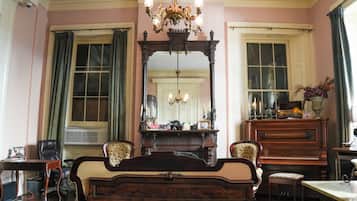 Quarto com um espelho grande, uma cama de madeira, um piano e um lustre.