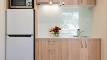 Uma cozinha compacta com armários de madeira, geladeira branca, micro-ondas e pia com torneira moderna.