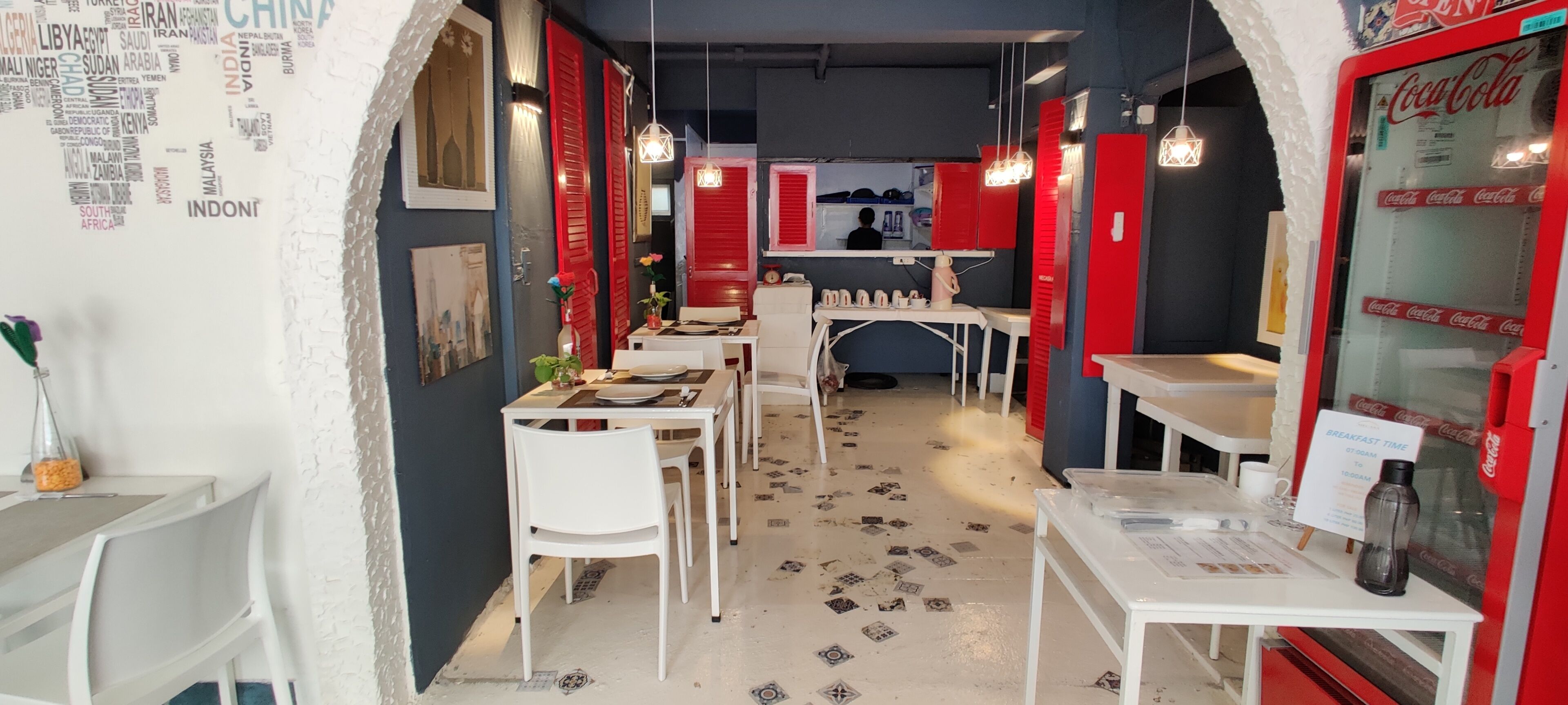 Restaurante com decoração em vermelho e branco, várias mesas e cadeiras.