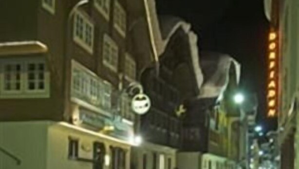 Ruas cobertas de neve à noite, com edifícios de ambos os lados.
