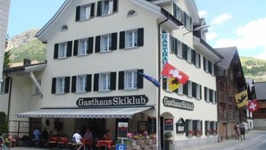 Um edifício com uma placa que diz "Gasthaus Skiklub" e uma bandeira suíça.