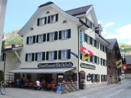 Um edifício com uma placa que diz "Gasthaus Skiklub" e uma bandeira suíça.