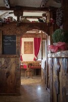 Um interior rústico de madeira com um quadro negro exibindo itens do cardápio, um banco de madeira e uma porta rústica.