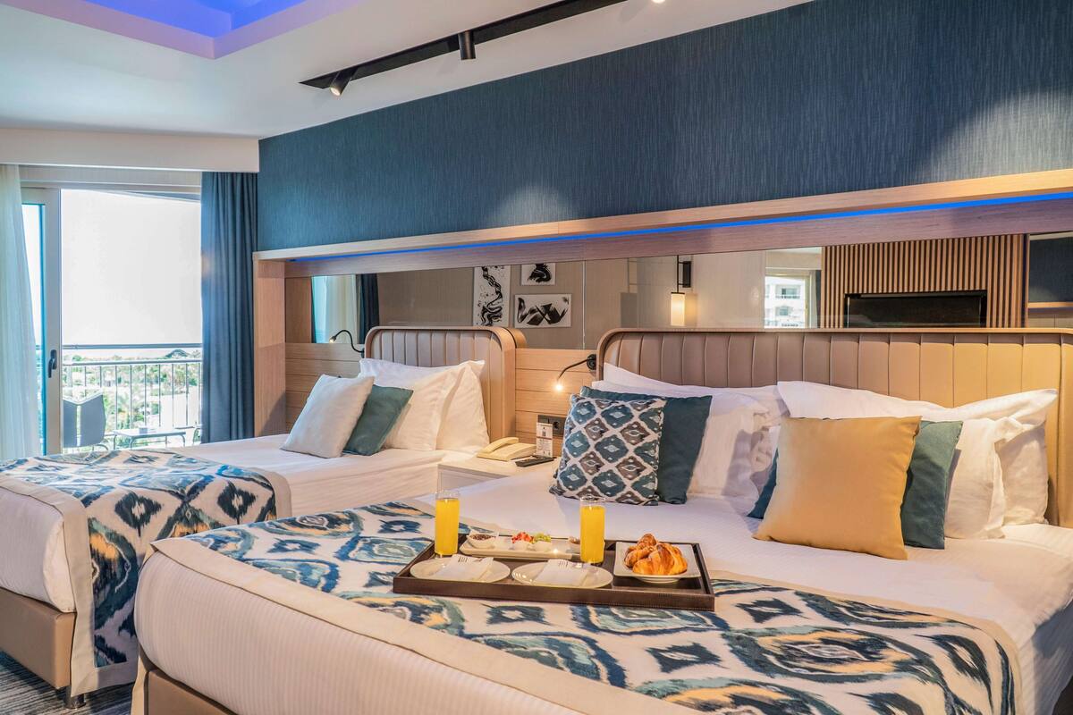 Quarto de hotel com duas camas, bandeja de café da manhã e vista para a varanda.