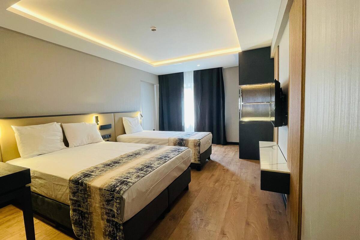 Quarto de hotel com duas camas, uma escrivaninha e uma televisão.