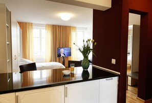 Quarto de hotel com cama, televisão, um vaso com flores e bandeja de café da manhã.