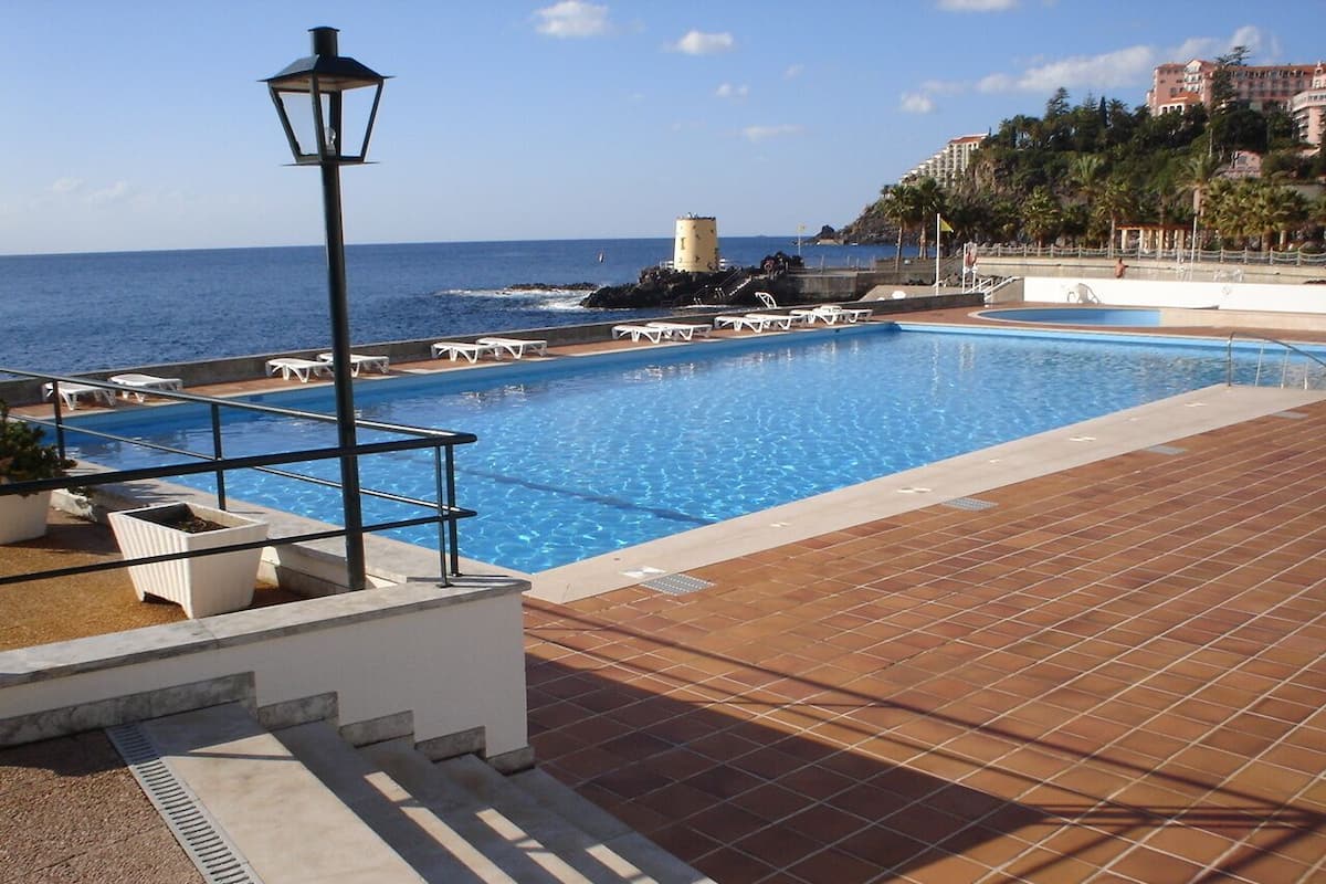 Piscina com vista para o oceano e uma torre ao fundo.