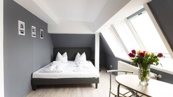 Quarto moderno com cama, mesa com um vaso de flores e janela com vista.