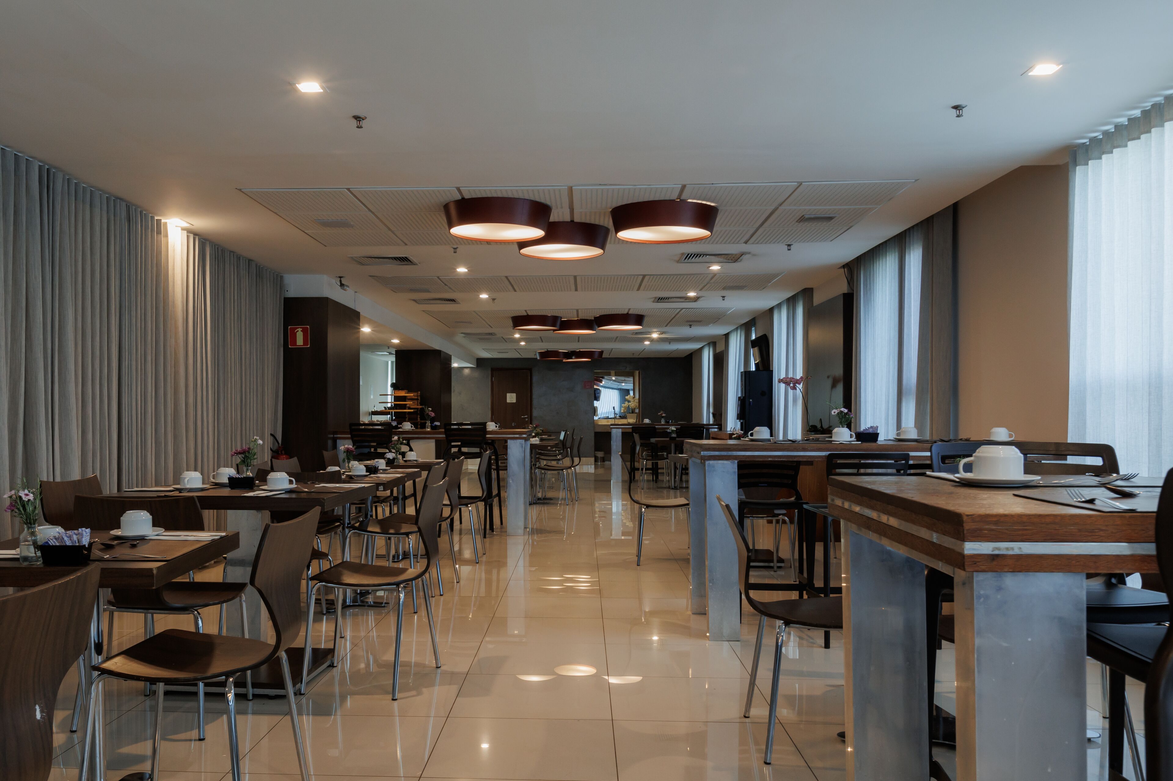 Um restaurante moderno com um balcão comprido, várias mesas e cadeiras.