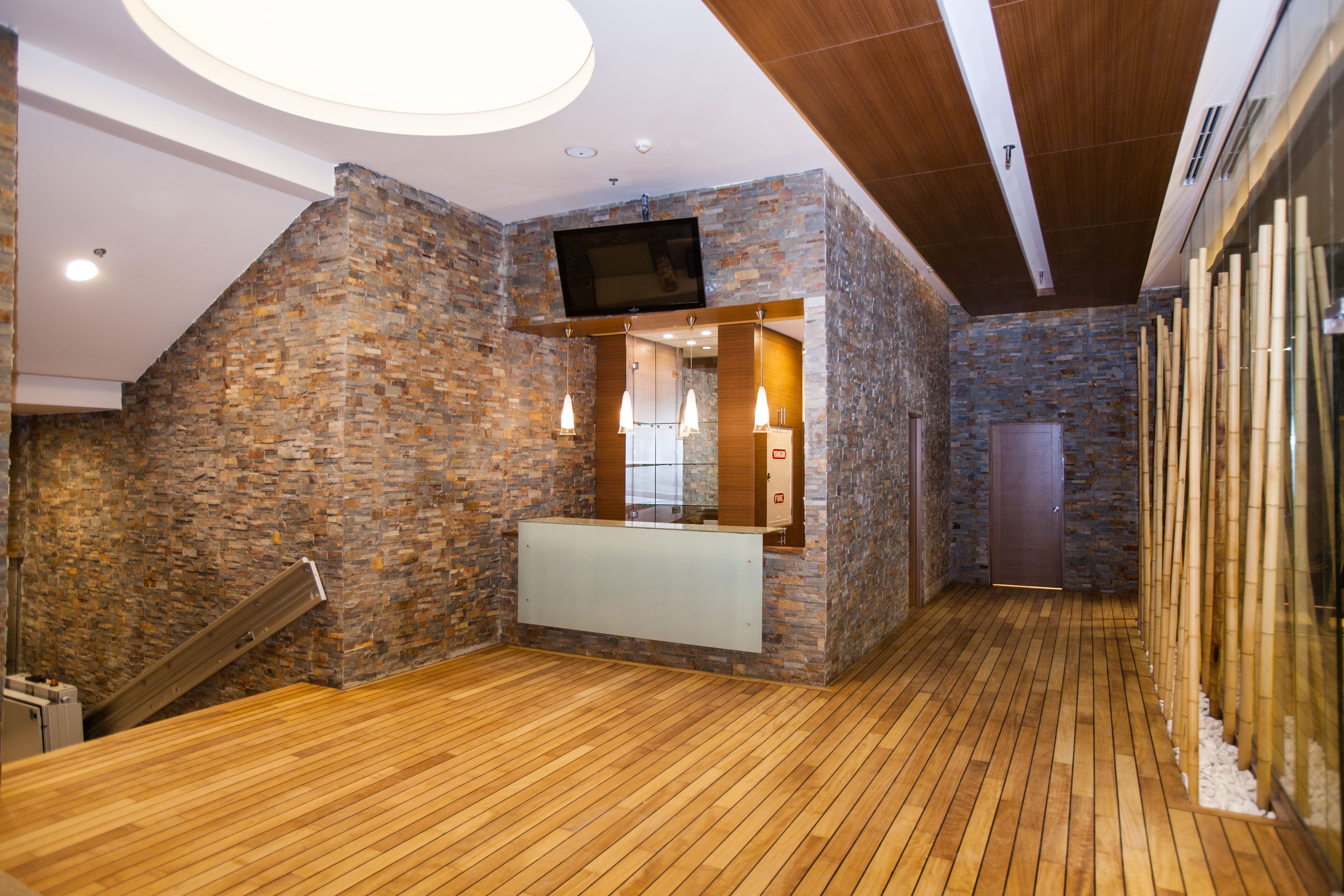 Espaço de spa com parede de pedra, piso de madeira e balcão de recepção.