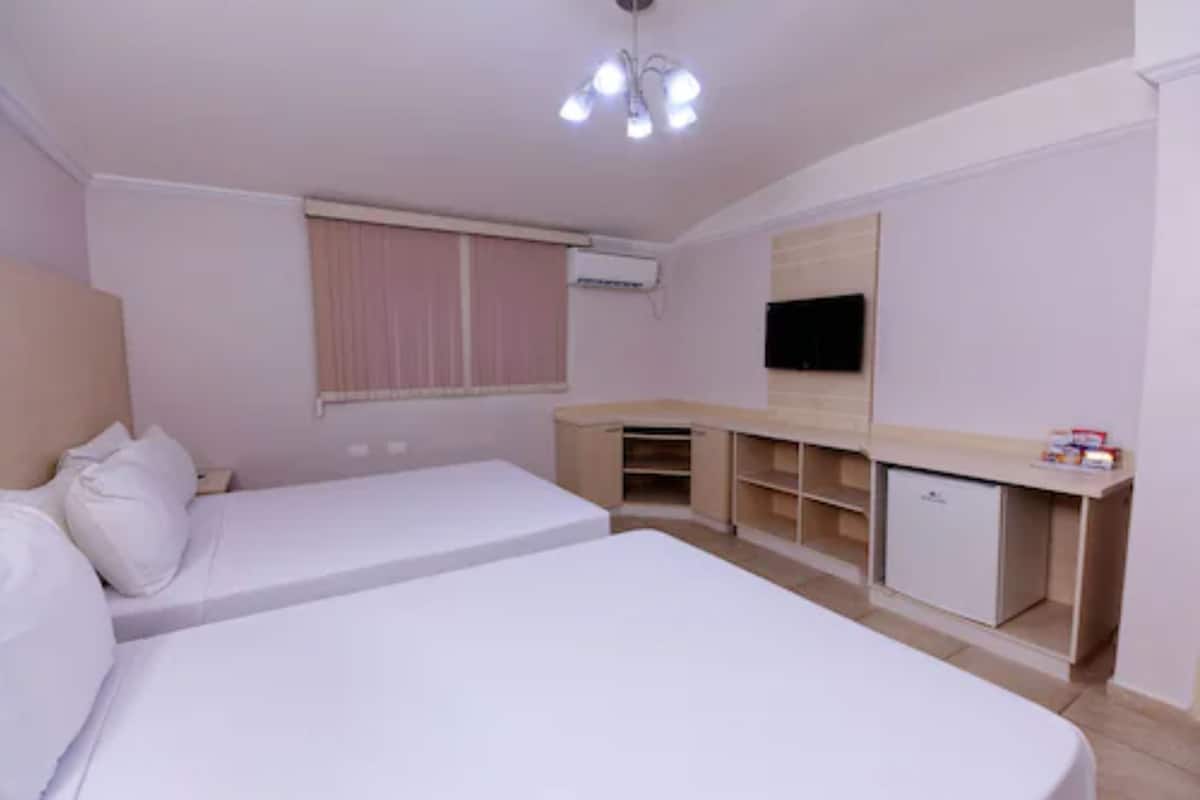 Quarto com duas camas, televisão, guarda-roupa e secretária.