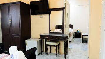 Quarto com cama, penteadeira, televisão e espelho.