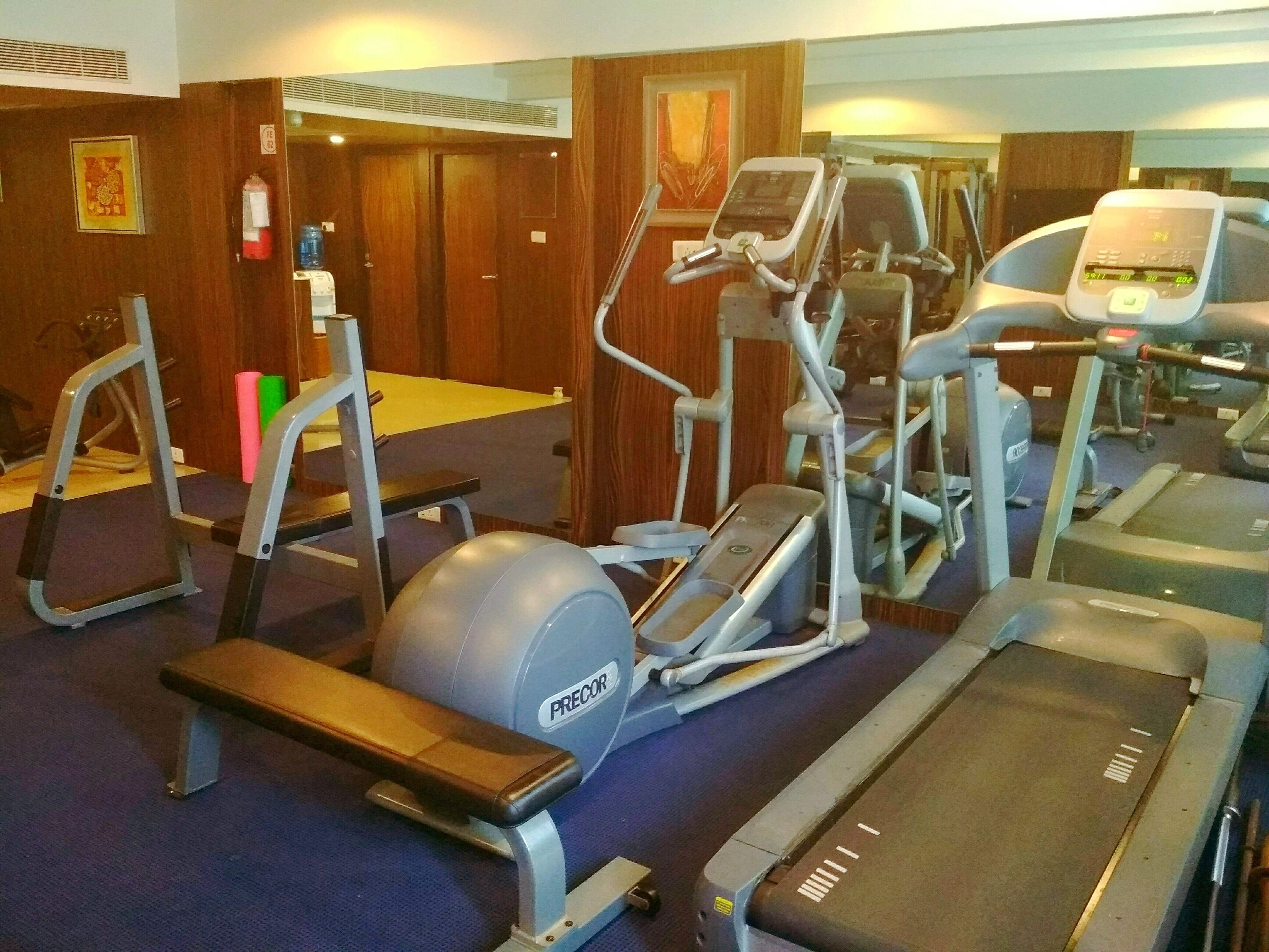 Uma academia com diversos equipamentos de exercício, incluindo esteiras, elípticos e aparelhos de musculação.