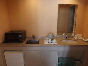 Uma cozinha compacta com micro-ondas, pia e pequeno frigorífico.