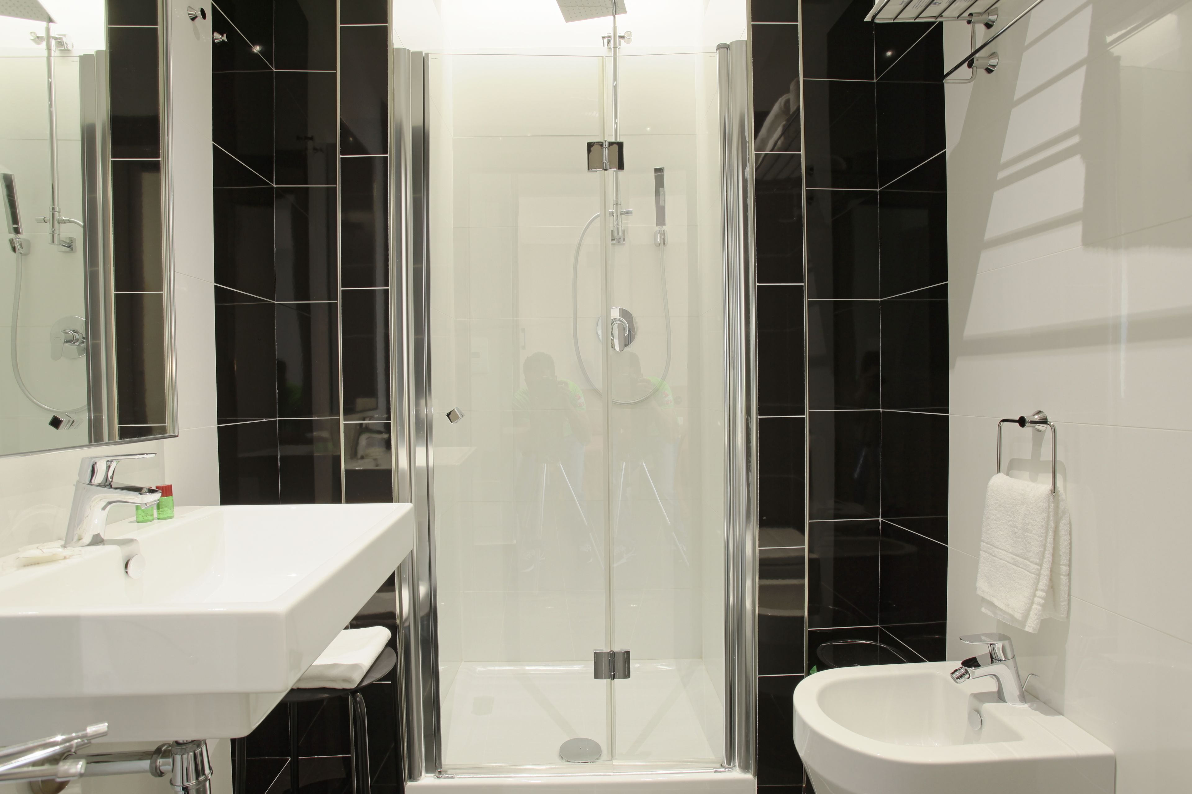 Casa de banho moderna com chuveiro envidraçado, lavatório branco e espelho.