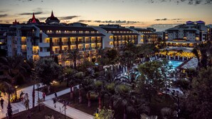 Um hotel com vários edifícios, piscina e palmeiras.
