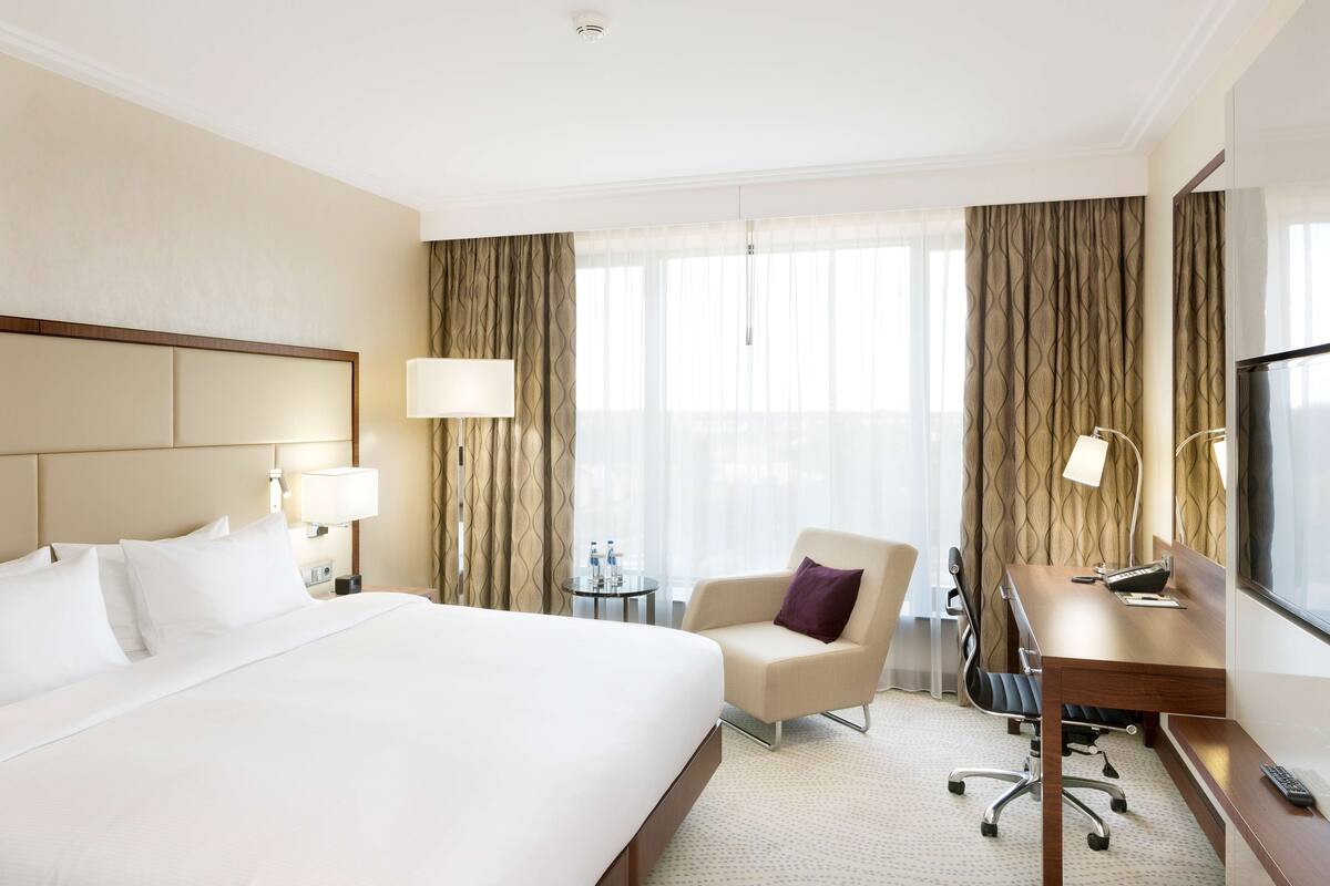 Quarto de hotel com uma cama grande, uma mesa, uma cadeira e uma televisão.