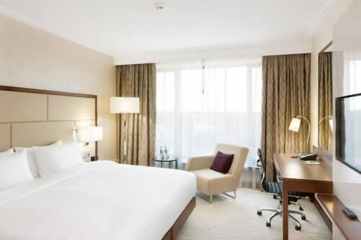Quarto de hotel com uma cama grande, uma mesa, uma cadeira e uma televisão.