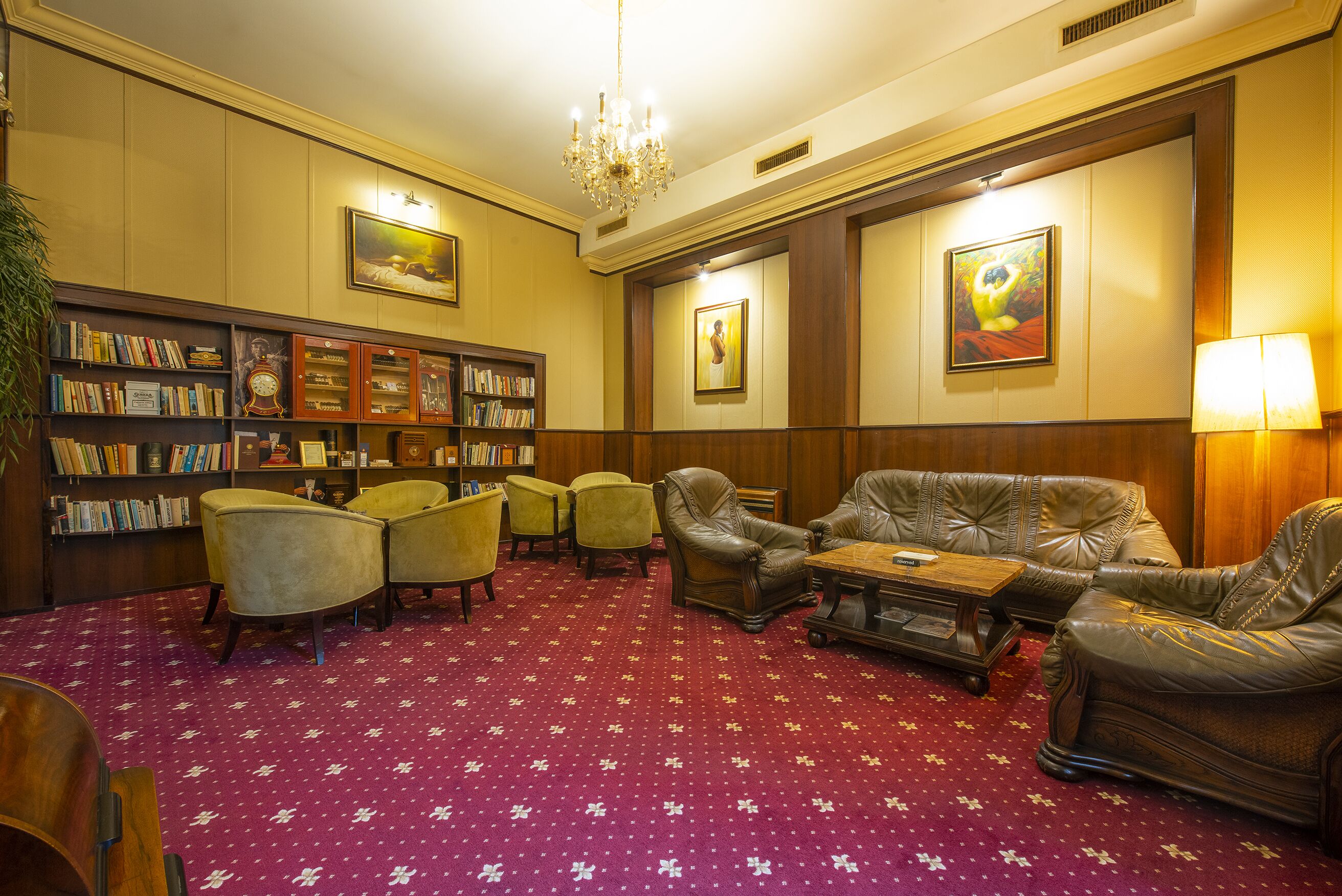 Uma biblioteca com poltronas de couro, uma mesa de centro de madeira e estantes de livros.