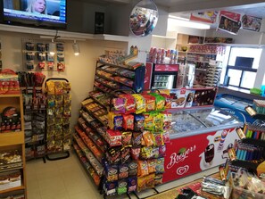 Uma loja de conveniência com prateleiras repletas de lanches, bebidas e outros produtos.