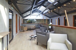 Amplo espaço interno com teto alto, móveis modernos e vista através de grandes janelas.