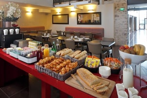 Um buffet de café da manhã com diversos pães, bolos e bebidas.