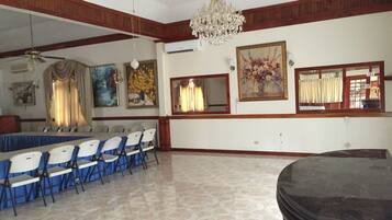 Uma sala de conferências com uma mesa comprida, cadeiras, um lustre e obras de arte nas paredes.