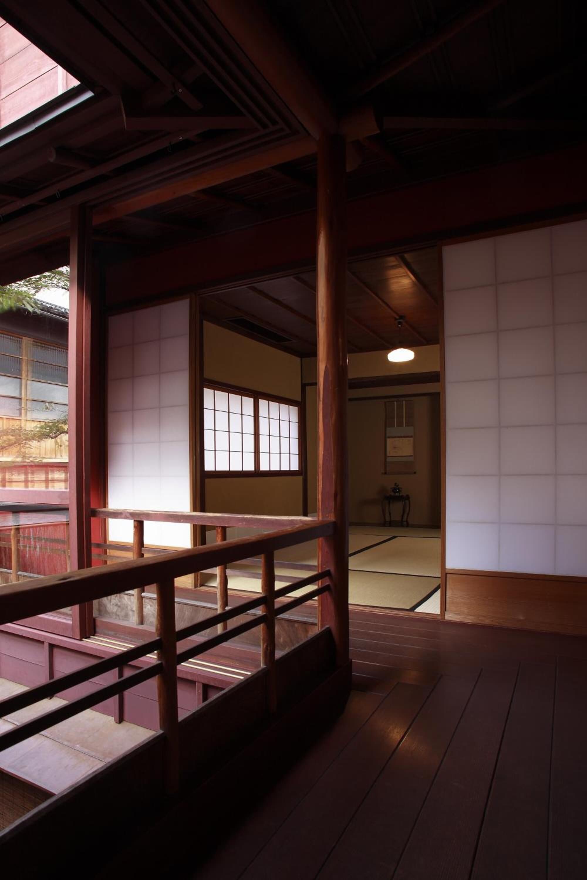 Um quarto japonês tradicional com tatames, vigas de madeira e portas deslizantes.