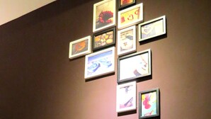 Parede com quadros emoldurados e uma mesa branca.