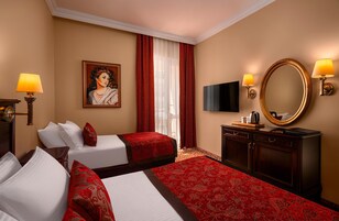 Quarto de hotel com duas camas, televisão, um espelho grande e um quadro na parede.