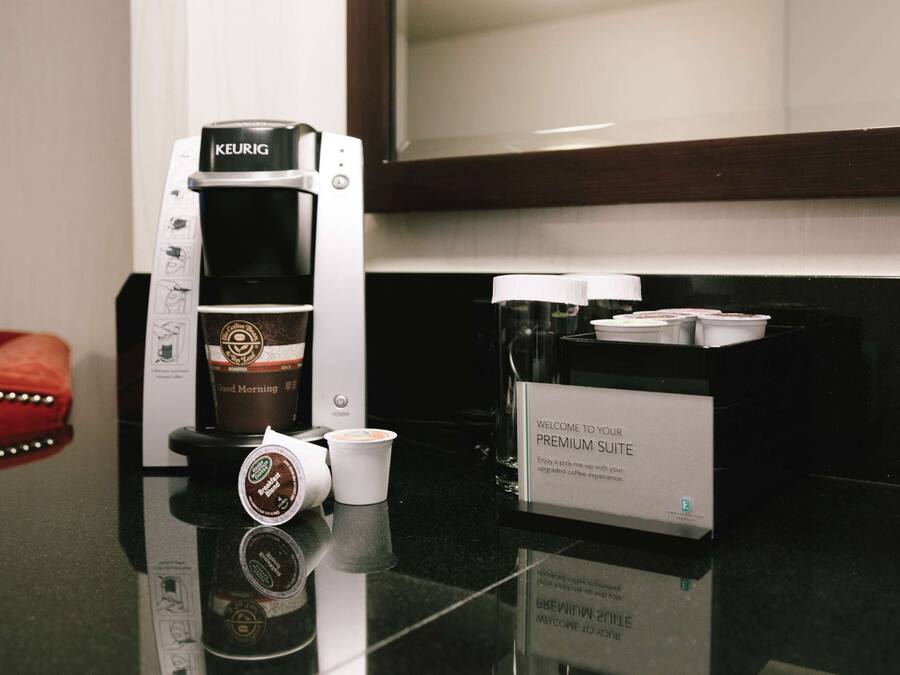 Máquina de café Keurig, cápsulas de café e um letreiro de boas-vindas para uma suíte premium em um hotel.