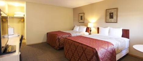 Quarto de hotel com duas camas, uma escrivaninha e um espelho.