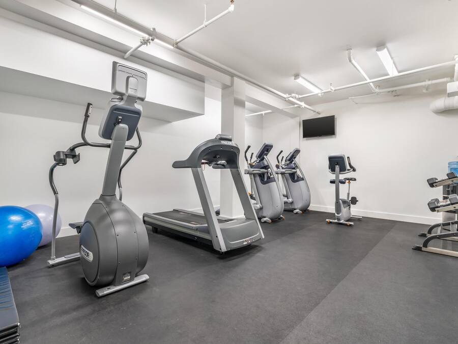 Uma academia com esteiras, elípticos e bolas de exercícios.