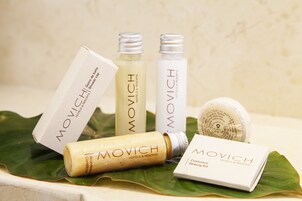 Um conjunto de artigos de higiene pessoal, incluindo touca de banho, frasco de condicionador e kit de costura, todos com a marca 'MOVICH HOTELS & RESORTS'.